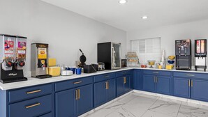 Uma cozinha moderna com armários azuis, uma máquina de café, uma torradeira e um refrigerador.