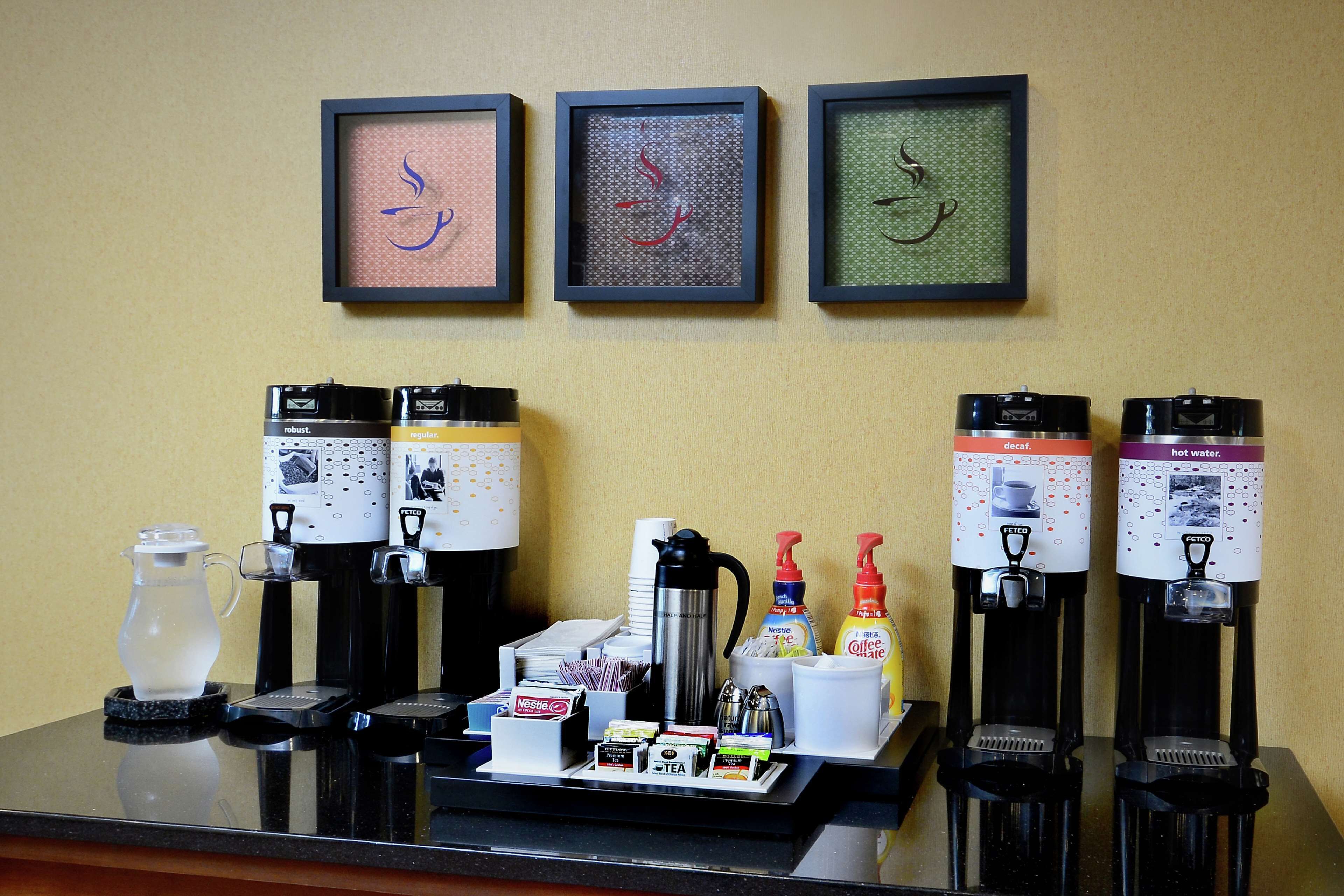 Uma estação de café com vários dispensadores, um espumador de leite e um jarro de leite.