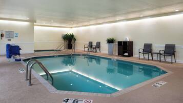 Piscina interna com indicador de profundidade de 1,40 metros, cercada por espreguiçadeiras e um elevador de piscina azul.