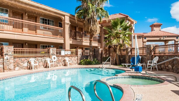 Um hotel com área de piscina, paredes de pedra e uma palmeira.