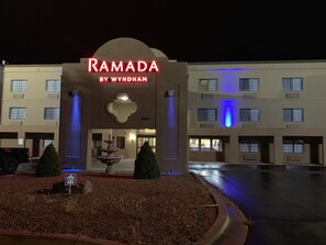 Entrada de hotel com um letreiro de neon que diz 'RAMADA BY WYNDHAM' e o número '3450'.