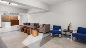 Uma área de recepção moderna com um balcão de madeira, um sofá e duas poltronas azuis.