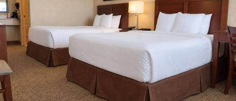 Quarto de hotel com duas camas, uma escrivaninha e uma cadeira.