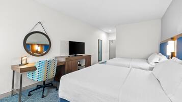 Quarto de hotel com uma cama grande, uma escrivaninha com cadeira, televisão e espelho.