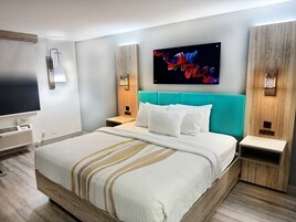 Quarto de hotel moderno com uma cama grande, televisão de tela plana e uma obra de arte na parede.