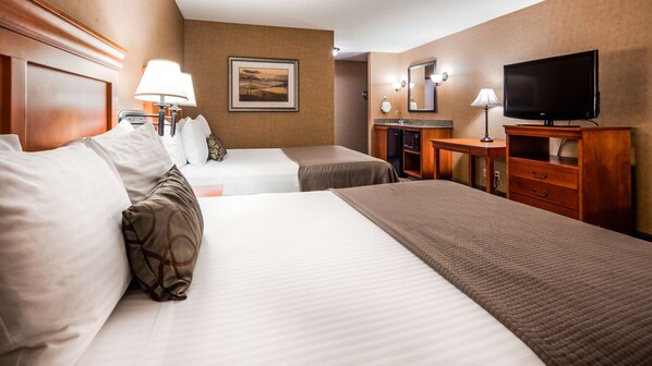 Quarto de hotel com duas camas, uma mesa de escritório, televisão e um quadro na parede.