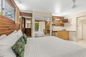Quarto com uma cama grande, uma escrivaninha e uma televisão.