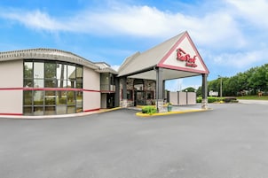 Um Red Roof Inn com design moderno, destacando uma ampla entrada de vidro e uma área de estar coberta.