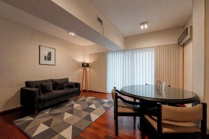 Uma sala de estar moderna com sofá, mesa de centro e mesa de jantar com cadeiras.