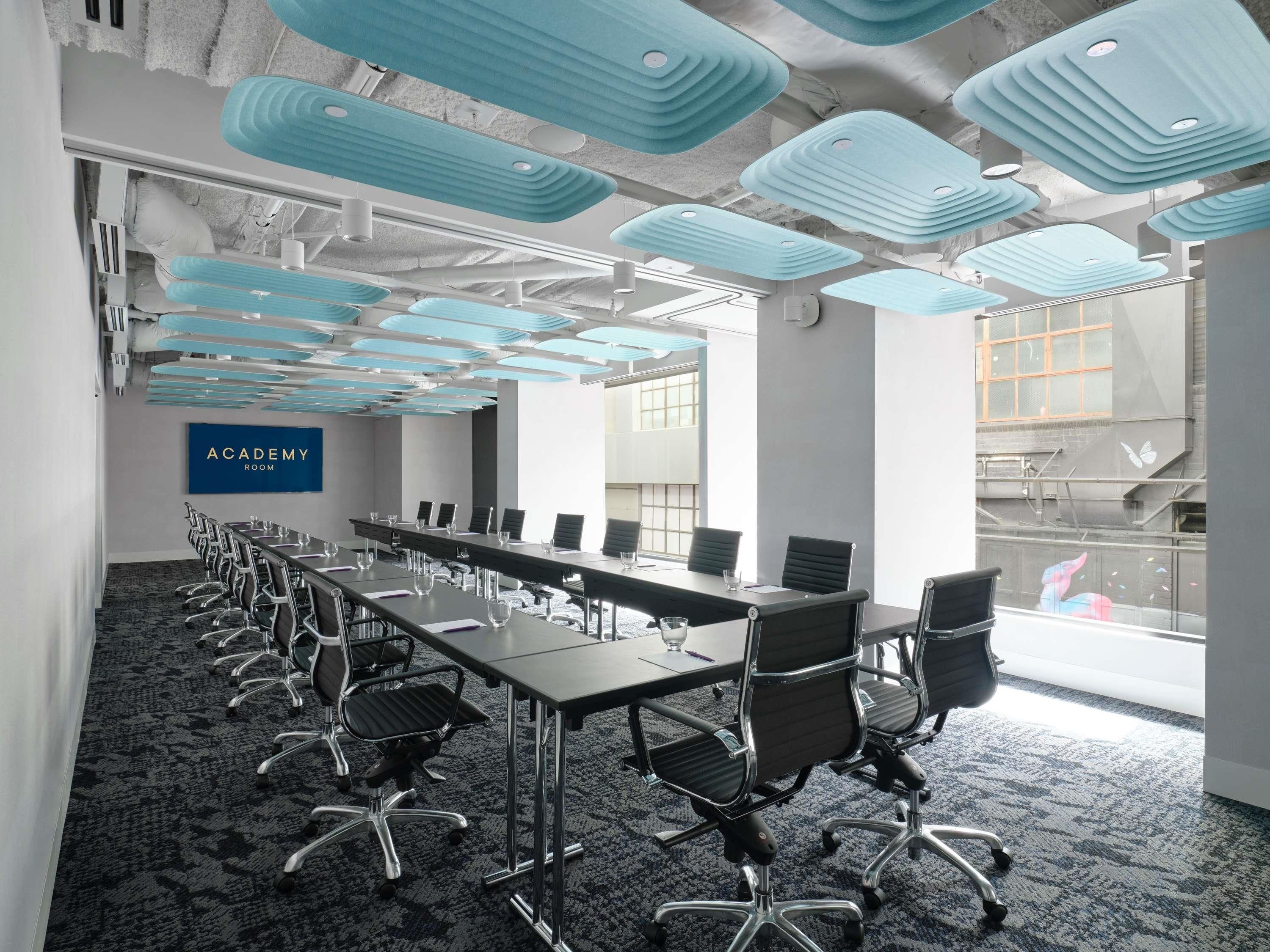 Uma sala de conferências com uma mesa comprida, cadeiras e um letreiro com a inscrição 'ACADEMY ROOM'.