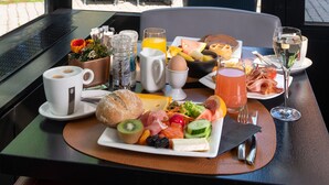 Mesa de café da manhã com diversos alimentos, uma xícara de café e um copo de suco de laranja.