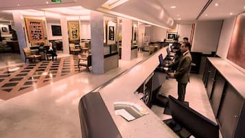 Um hall de hotel moderno com balcão de recepção, área de estar e obras de arte nas paredes.
