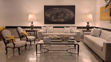 Uma sala de estar moderna com um quadro abstrato grande, duas mesas laterais com luminárias e uma mesa de centro.