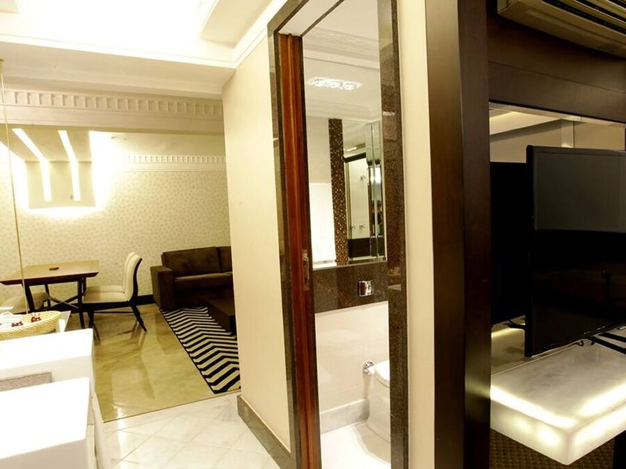 Quarto de hotel com banheiro, área de estar e televisão.