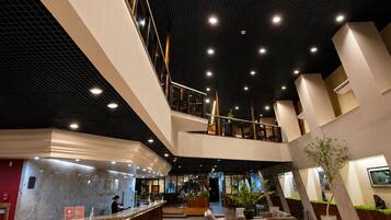 Um hall amplo com balcão de recepção, área de estar e um mezanino.