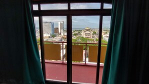 Quarto com uma grande janela que dá para a paisagem urbana, incluindo um edifício imponente com cúpula.
