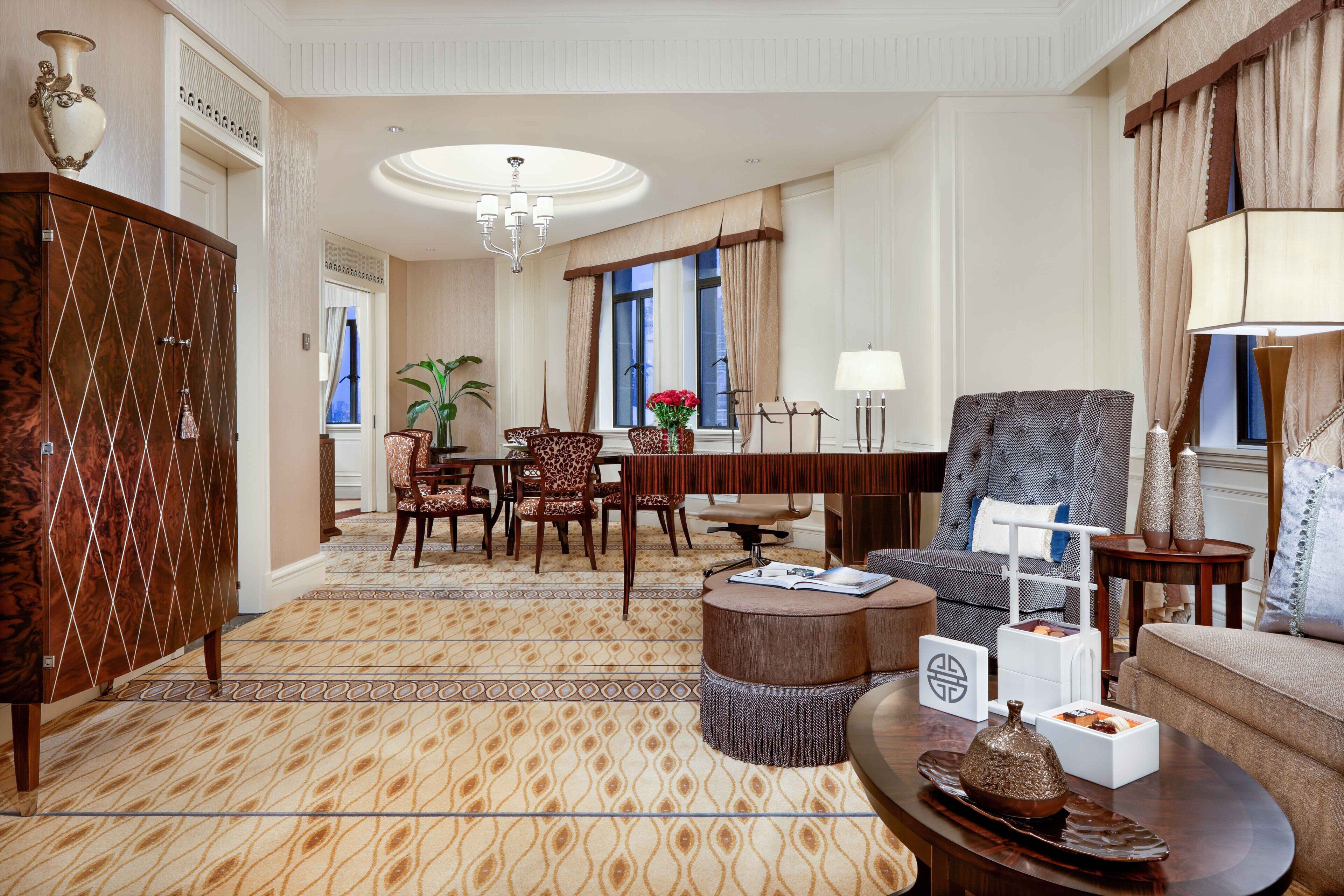 Quarto de hotel com área de refeições, um sofá, uma cadeira e uma mesa decorativa.