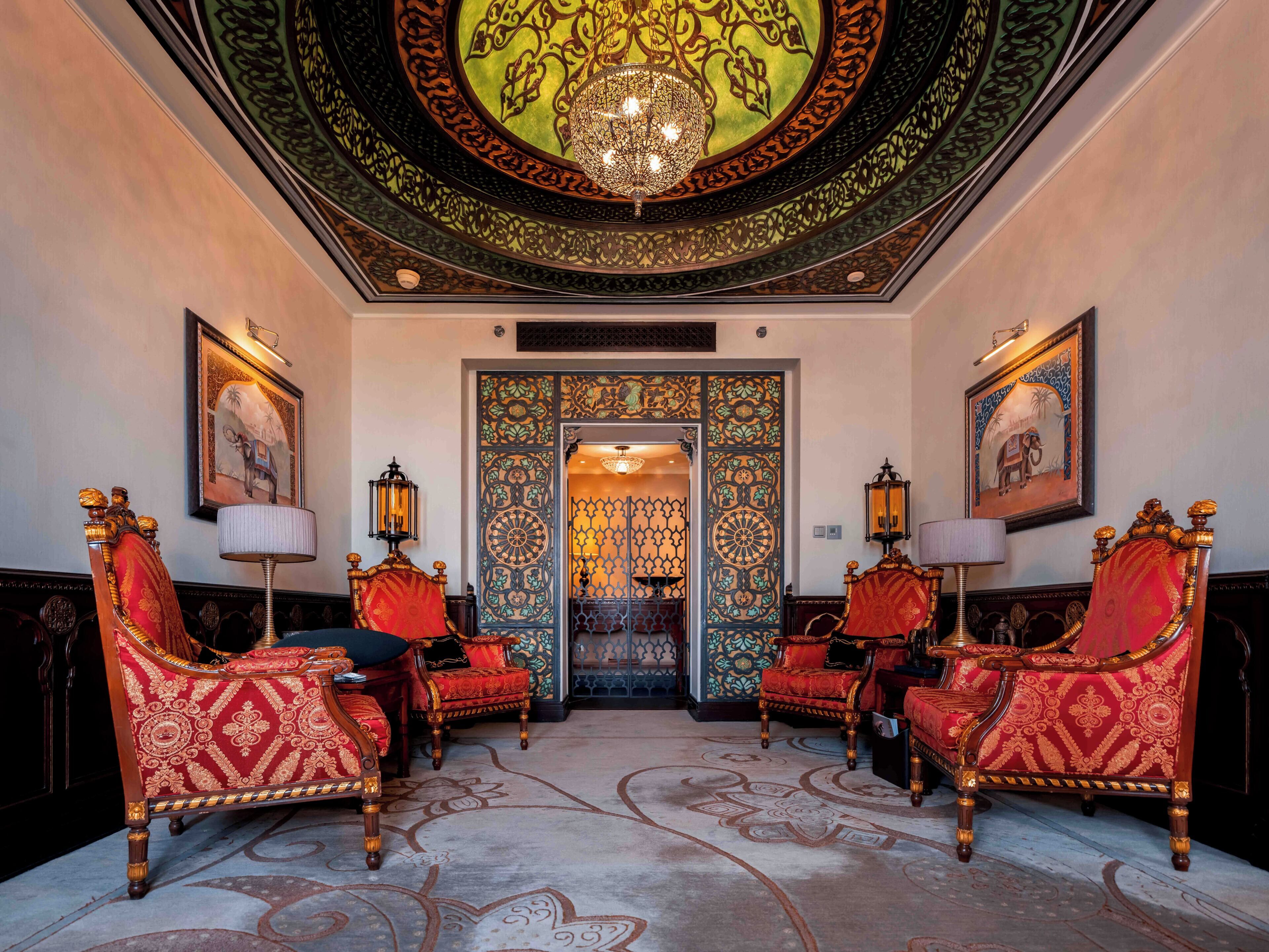 Quarto luxuoso com mobiliário requintado, tapete estampado e teto decorativo.