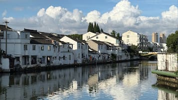 Uma cidade às margens do rio, com edifícios brancos tradicionais, uma ponte e um corpo d'água calma que reflete as construções.