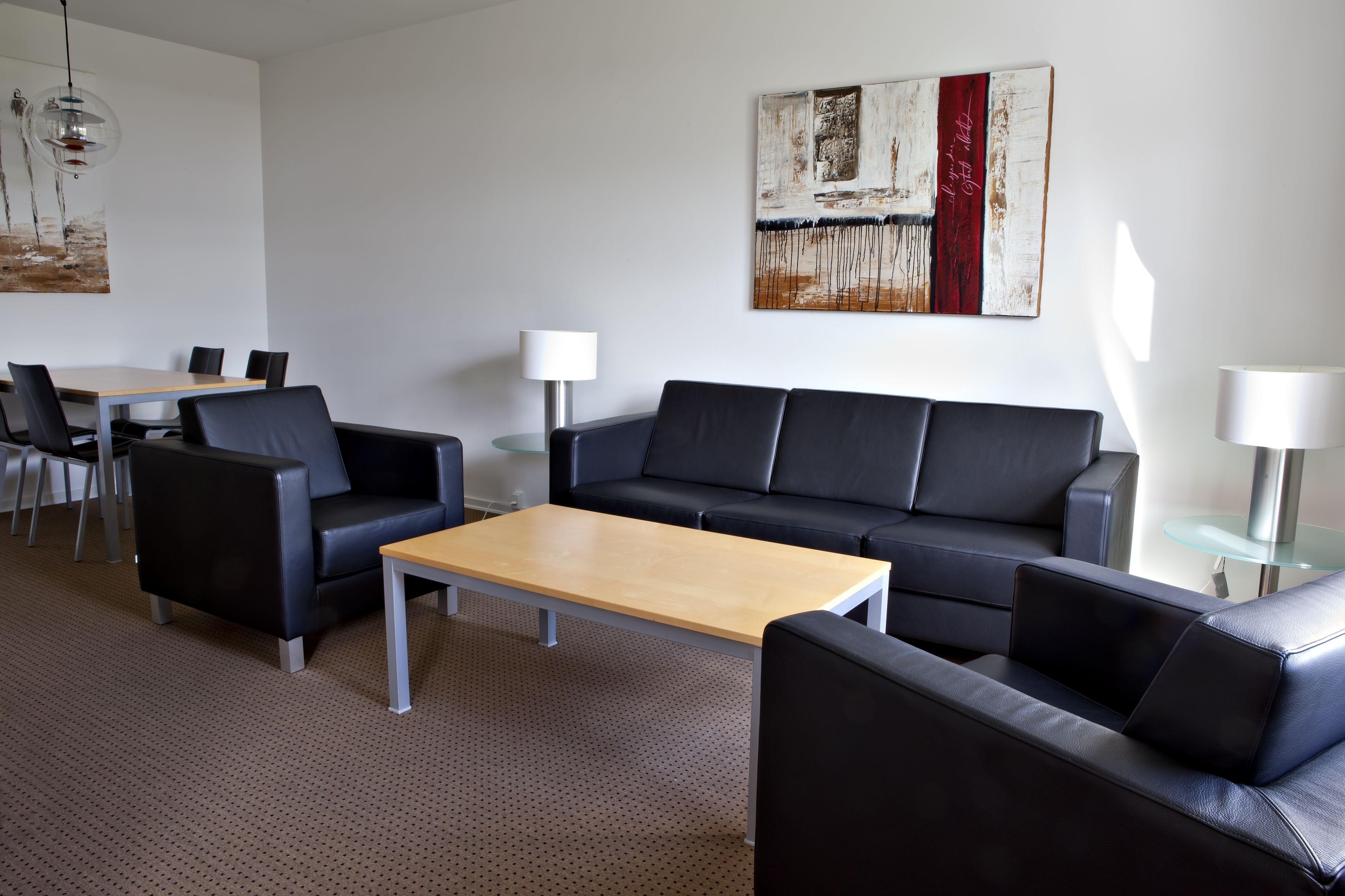 Uma área de estar moderna com um sofá, cadeiras, uma mesa de centro e uma mesa de vidro.