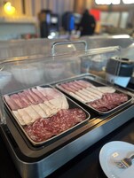 Um buffet com diversos tipos de carnes e queijos.