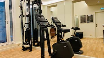 Uma academia com aparelhos de cardio, equipamentos de musculação e um espelho refletindo o espaço.