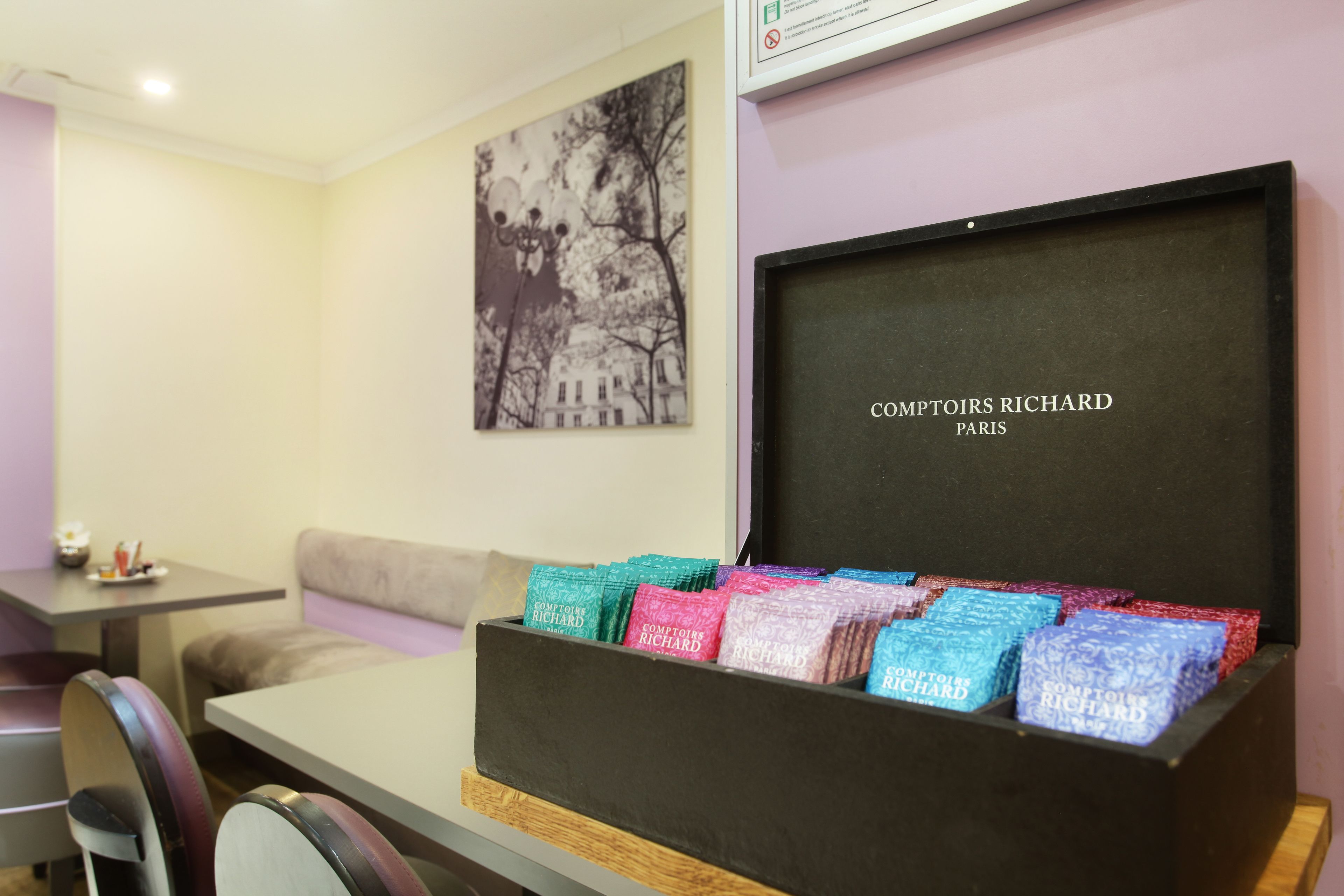 Um quarto com uma mesa, um sofá e uma vitrine com a identificação "Comptoirs Richard Paris" exibindo diversos objetos.