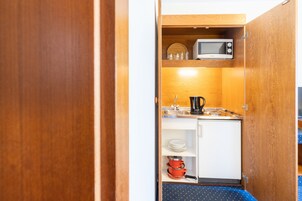 Uma cozinha compacta equipada com micro-ondas, pia e prateleiras para armazenamento.