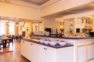 Uma área de buffet com diversos alimentos e um espaço de refeições com mesas e cadeiras.