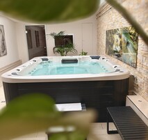 Uma banheira de hidromassagem em um banheiro moderno com parede de pedra e uma pintura.