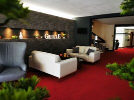 Uma sala de estar moderna com uma parede de destaque em pedra, uma lareira e uma placa com a inscrição 'GRILLE'.