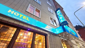 Um hotel com uma placa grande exibindo o nome e informações de contato.