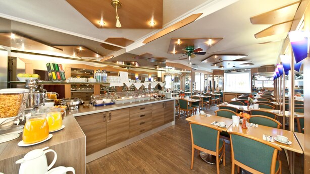 Um restaurante moderno com balcão central, várias mesas de jantar e diversas opções de assento.
