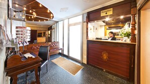 Uma área de recepção com uma mesa de madeira, balcão de recepção, um banco e um letreiro de recepção.