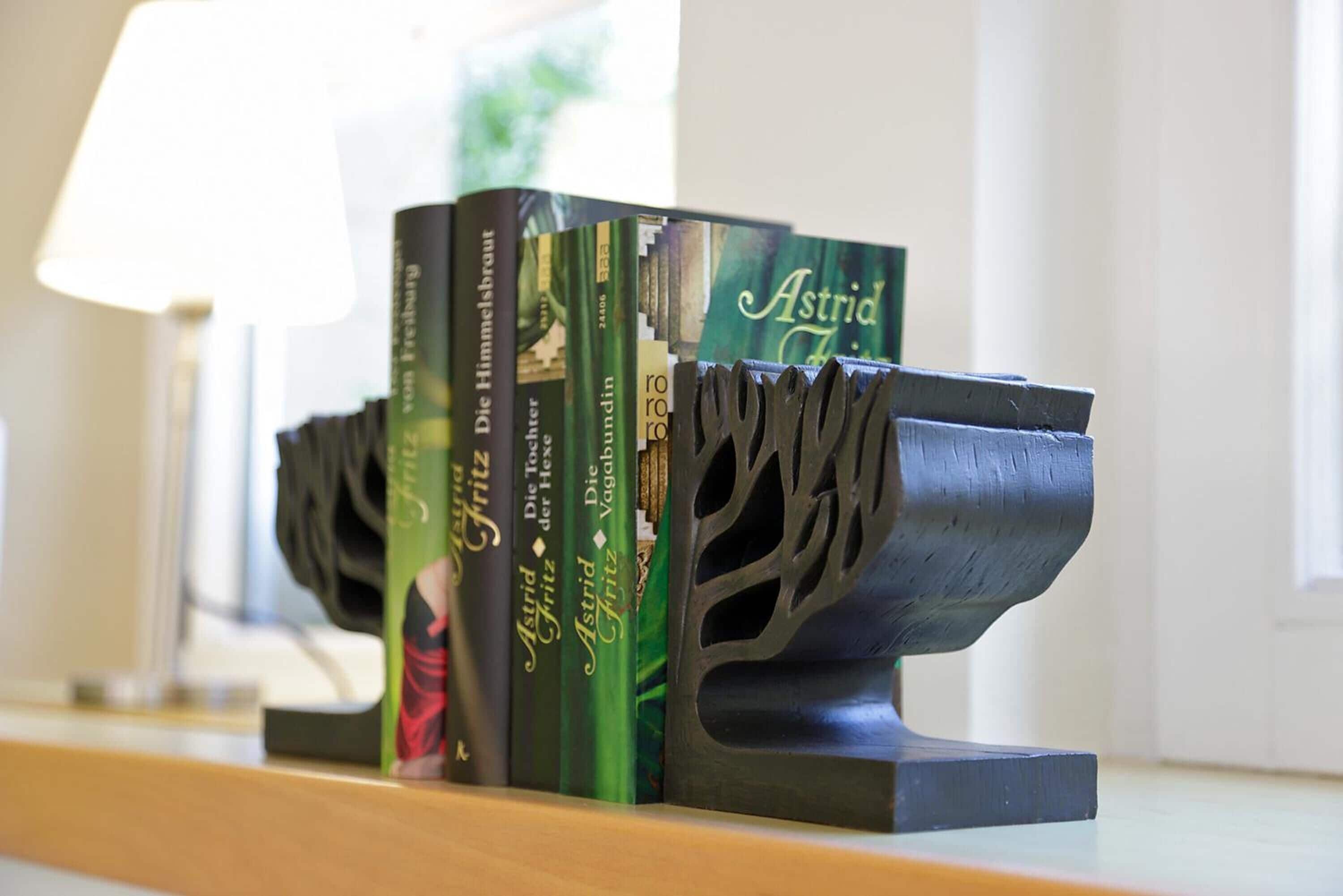 Uma estante de madeira com livros intitulados 'Astrid Fritz' e 'Die Heimelbraut'.