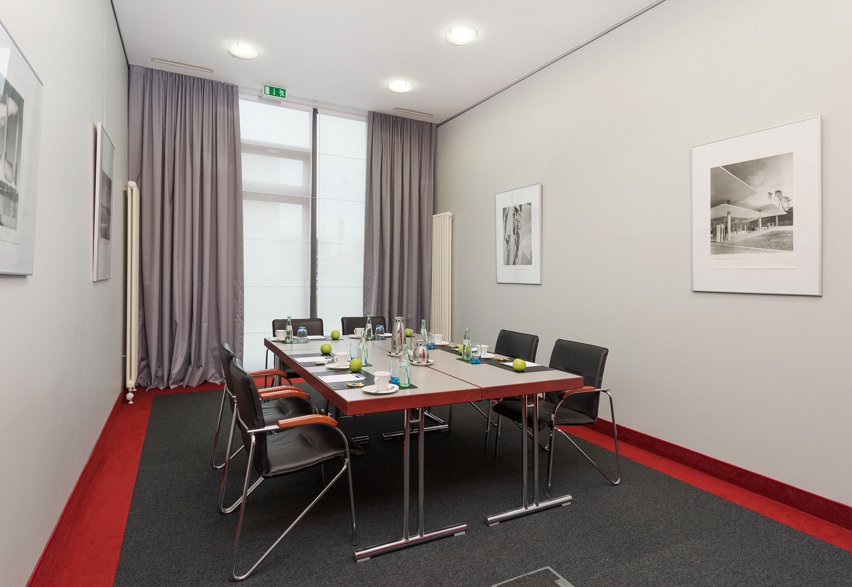 Uma sala de conferências com uma mesa comprida, cadeiras e um tapete vermelho.