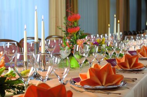Mesa posta para um jantar elegante, com velas, taças e arranjos florais.