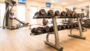 Uma academia com equipamentos de musculação, esteiras e aparelhos de exercício.