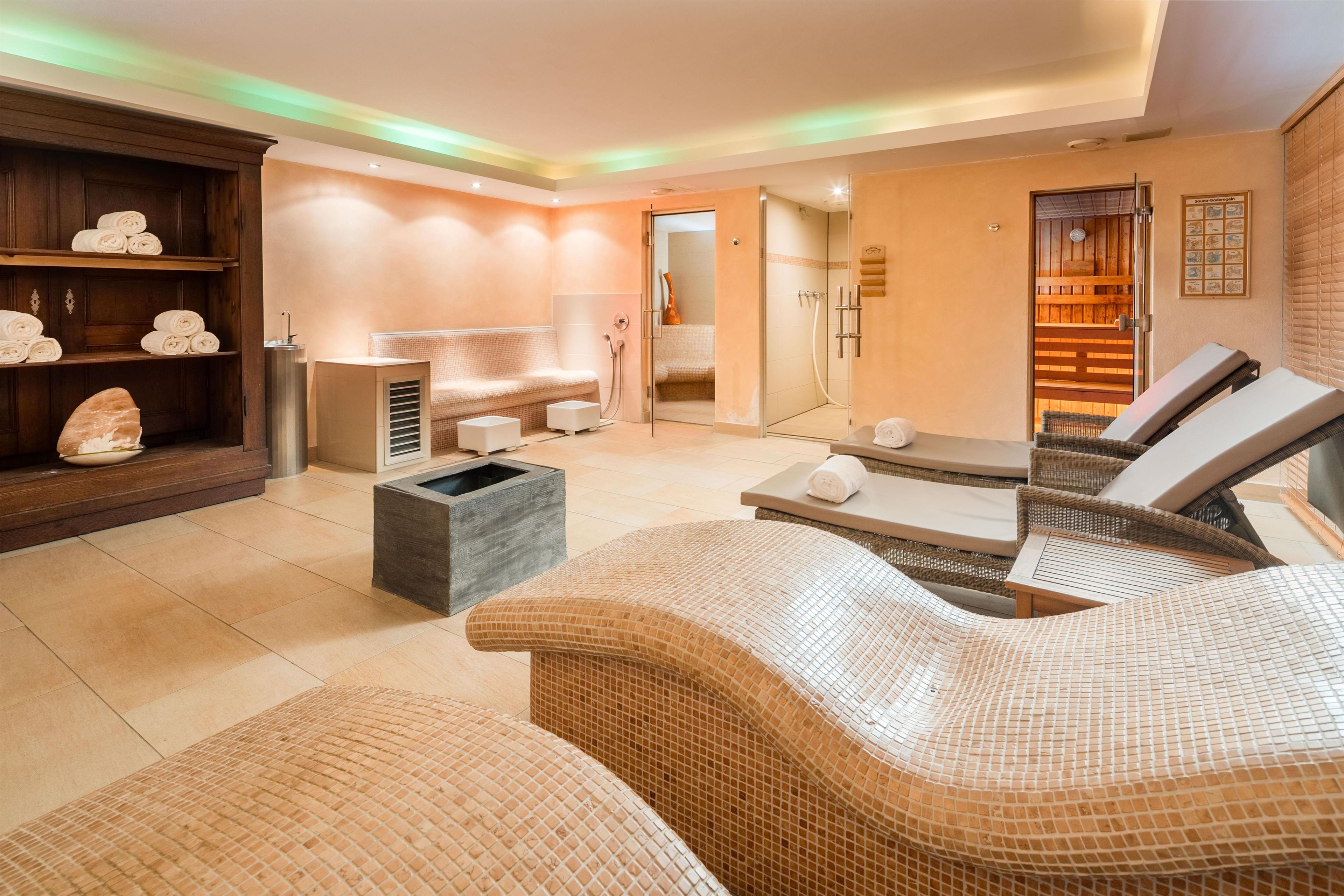 Uma área de spa moderna com espaço para sentar, mesa de massagem e casa de banho.