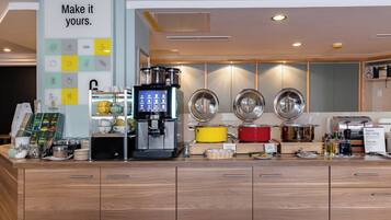 Cozinha moderna com cafeteira, torradeira e chaleira. Há diversos utensílios e eletrodomésticos sobre o balcão.