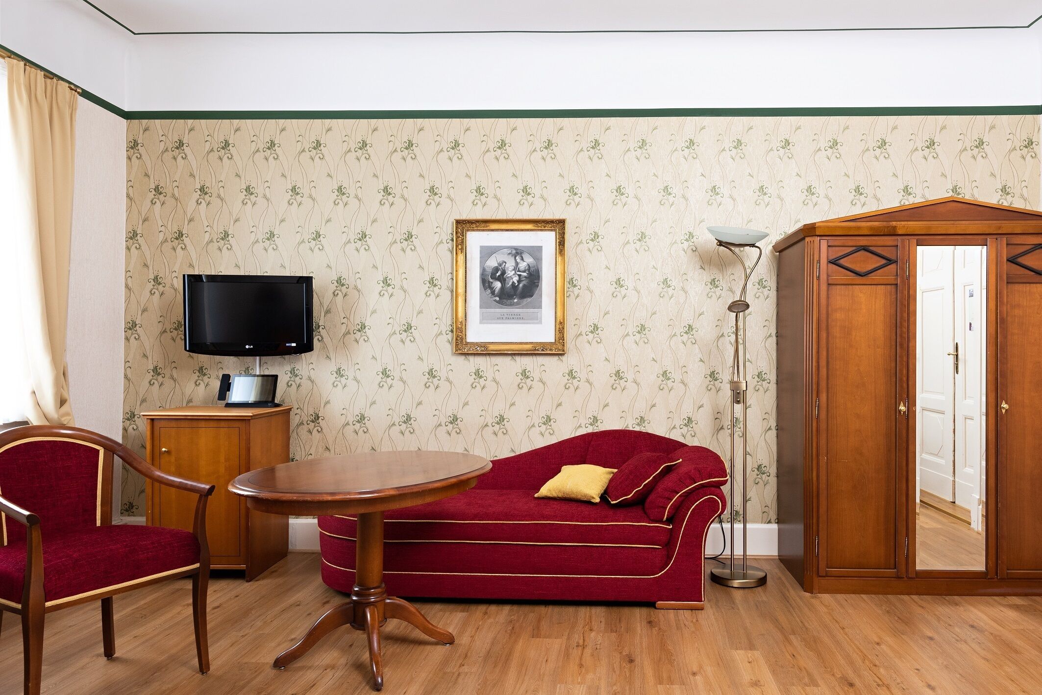 Quarto com sofá vermelho, armário de madeira e televisão sobre suporte.