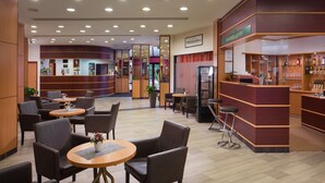 Um hall de hotel com mesas redondas, área de bar e assentos.