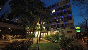 Um edifício de vários andares com varandas e uma área externa bem iluminada para sentar.