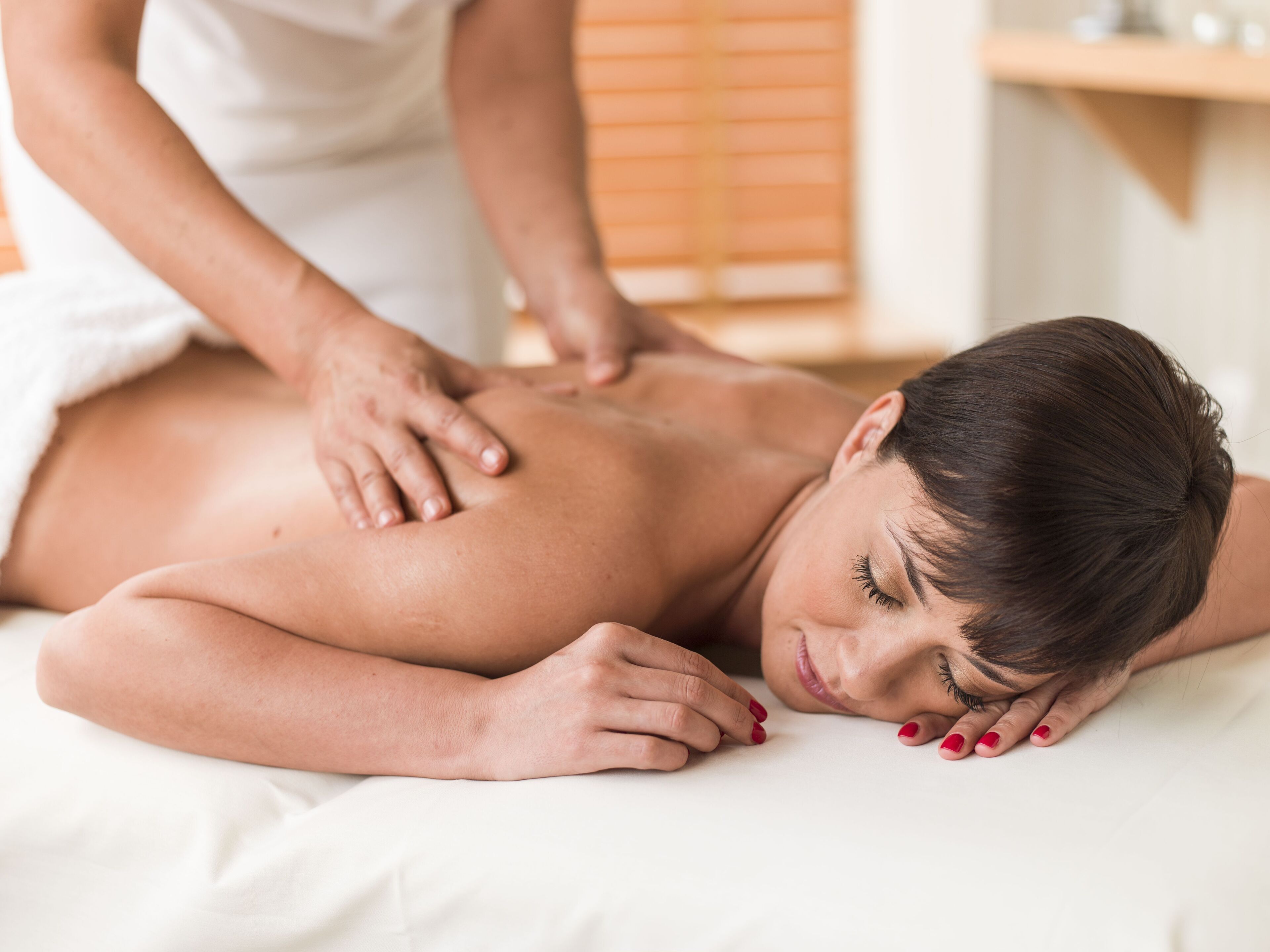 Uma pessoa recebendo uma massagem nas costas em uma cama.