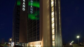 Um hotel com design arquitetônico moderno, destacando uma placa vertical proeminente e fachada de vidro.