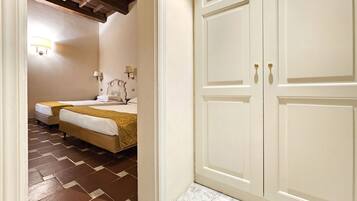 Quarto de hotel com duas camas, piso de mármore e guarda-roupa com portas duplas.