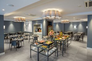 Uma área de refeições moderna com mesas de vidro, diversas opções de assento e vários displays de comida.