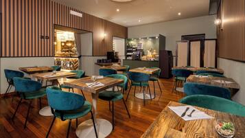 Um restaurante com mesas de madeira e cadeiras cor turquesa, área de bar e design de interiores moderno.