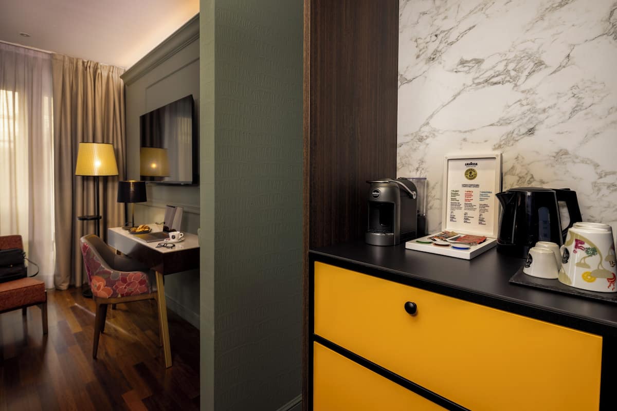 Quarto de hotel com escrivaninha, cadeira, cafeteira e um menu no balcão.