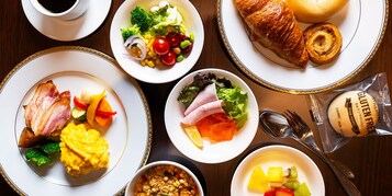 Uma mesa com diversos itens de café da manhã, incluindo croissants, ovos e frutas.